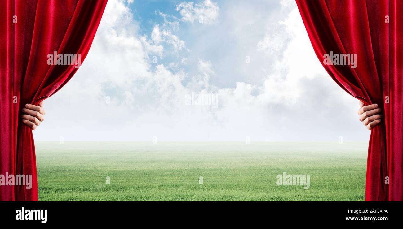 Green meadow behind red curtain and hand holding it Stock Photo - Alamy