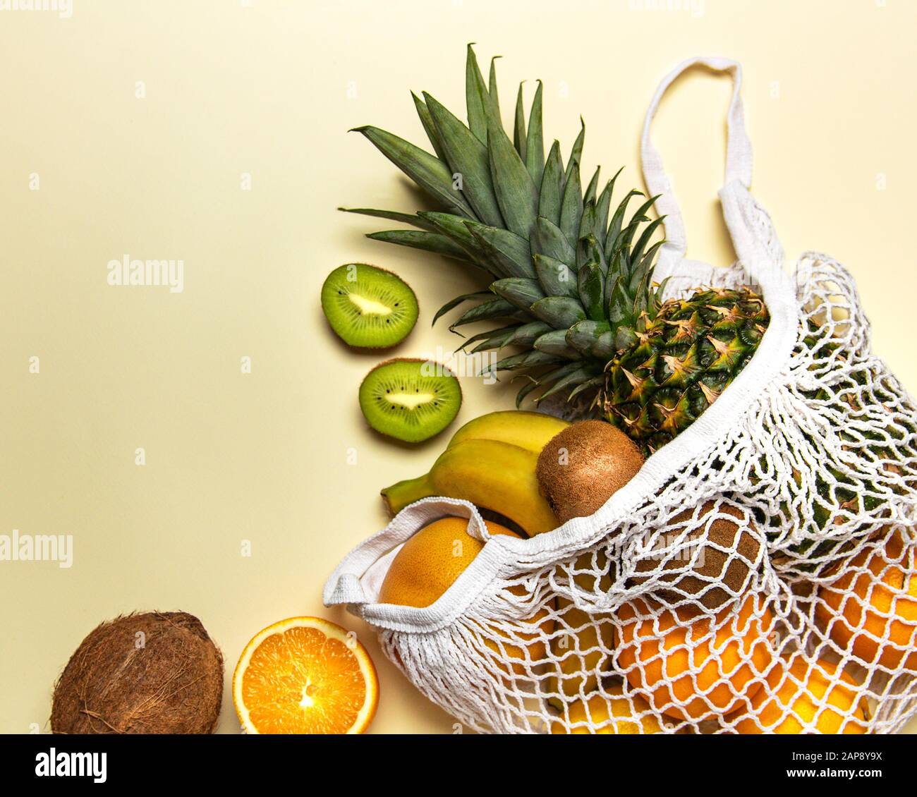 Mesh shopping bag with organic fruits on yellow background. Flat lay ...