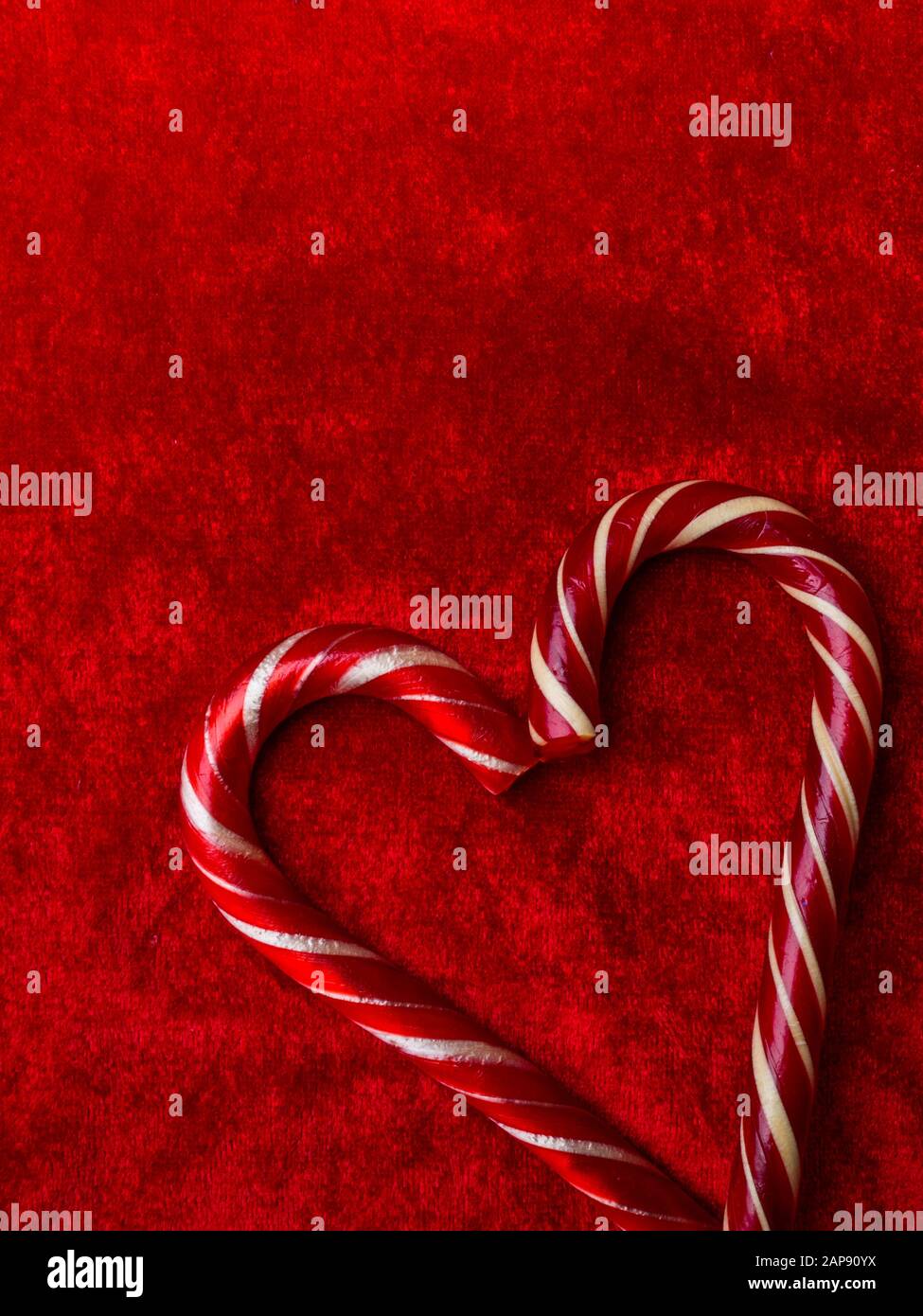 Two candy canes making a heart on a red textured background, Candy cane heart Stock Photo - Alamy