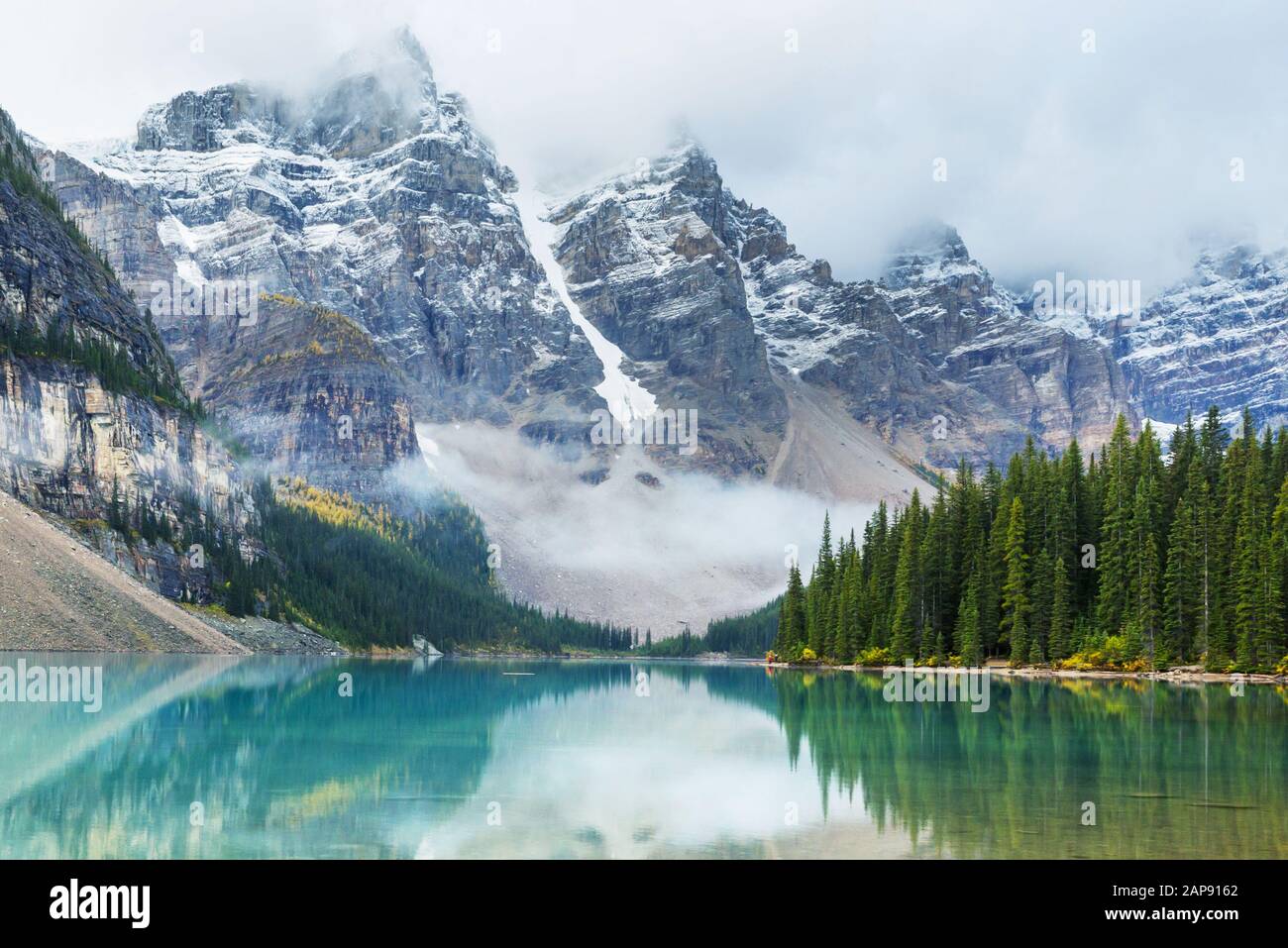 Beautiful turquoise waters of the Moraine lake with snow-covered peaks above it in Banff ...