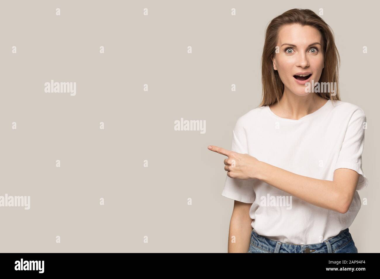 Surprised young woman point at blank copy space aside Stock Photo - Alamy