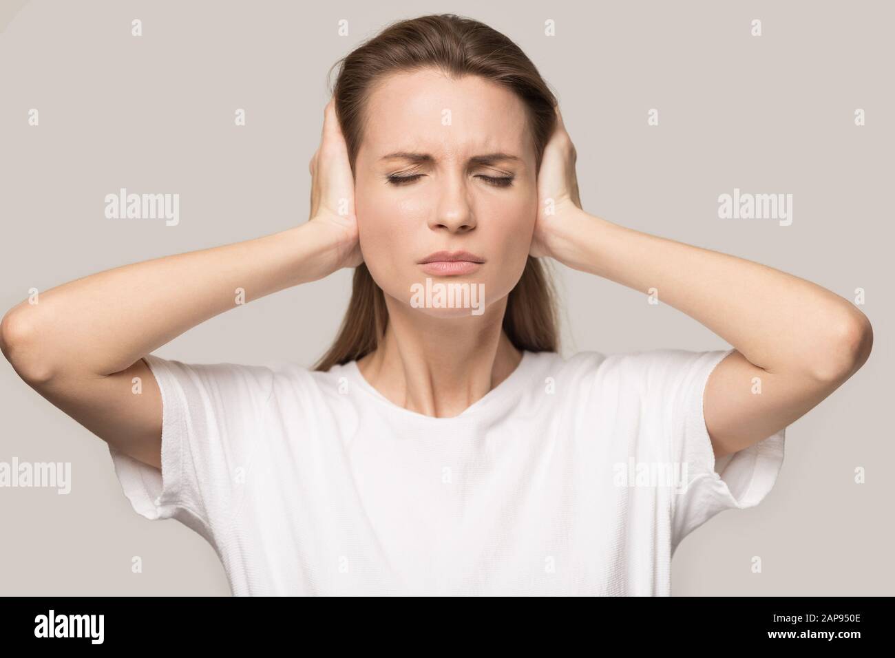 Annoyed young woman cover ears avoiding loud noises Stock Photo - Alamy