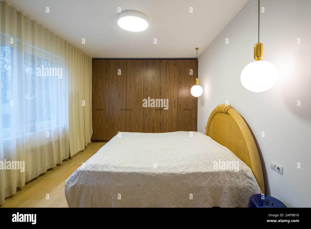 Modern light interior of bedroom. Side view of made-up bed with a round ...