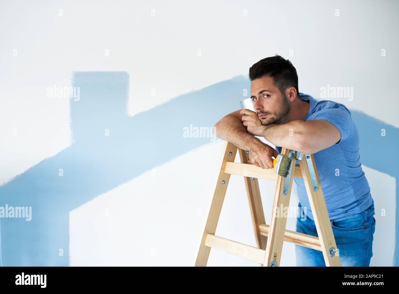 Portrait of bored and displeased man catching a break from painting ...