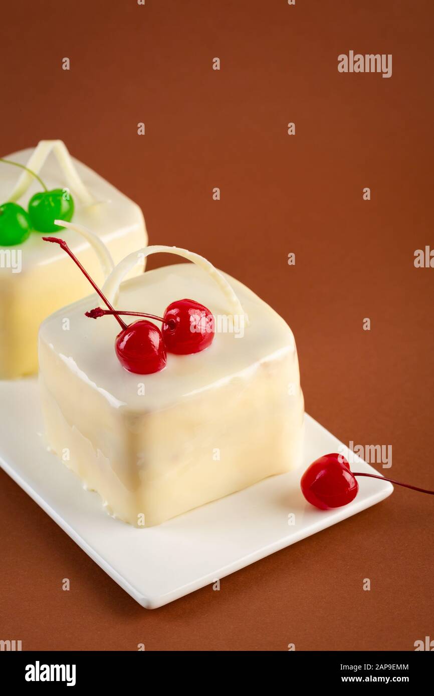 Two mousse portion cake with cherry on brown background Stock Photo - Alamy