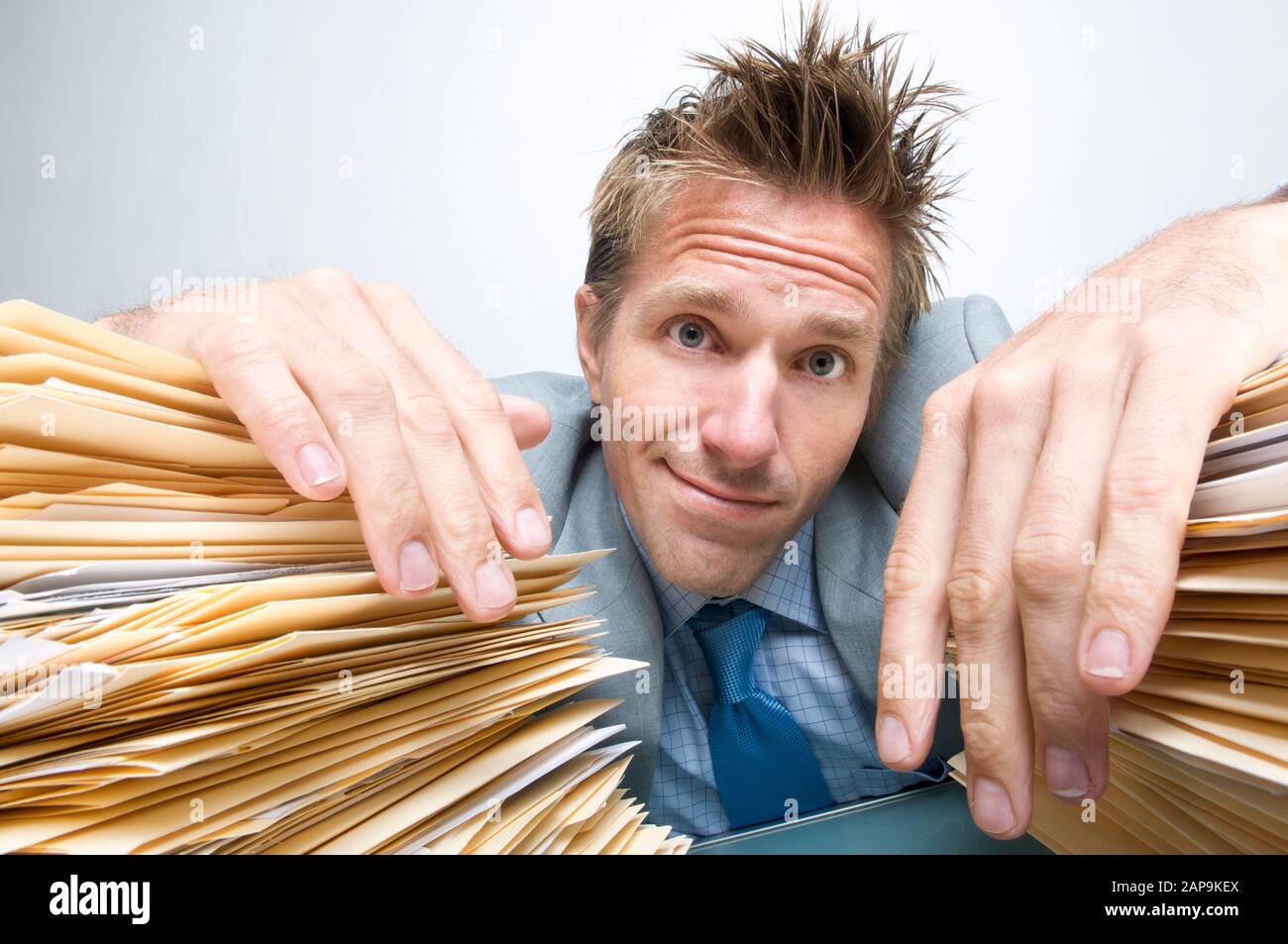 Office worker with huge pile of paperwork looking resigned to the work ...