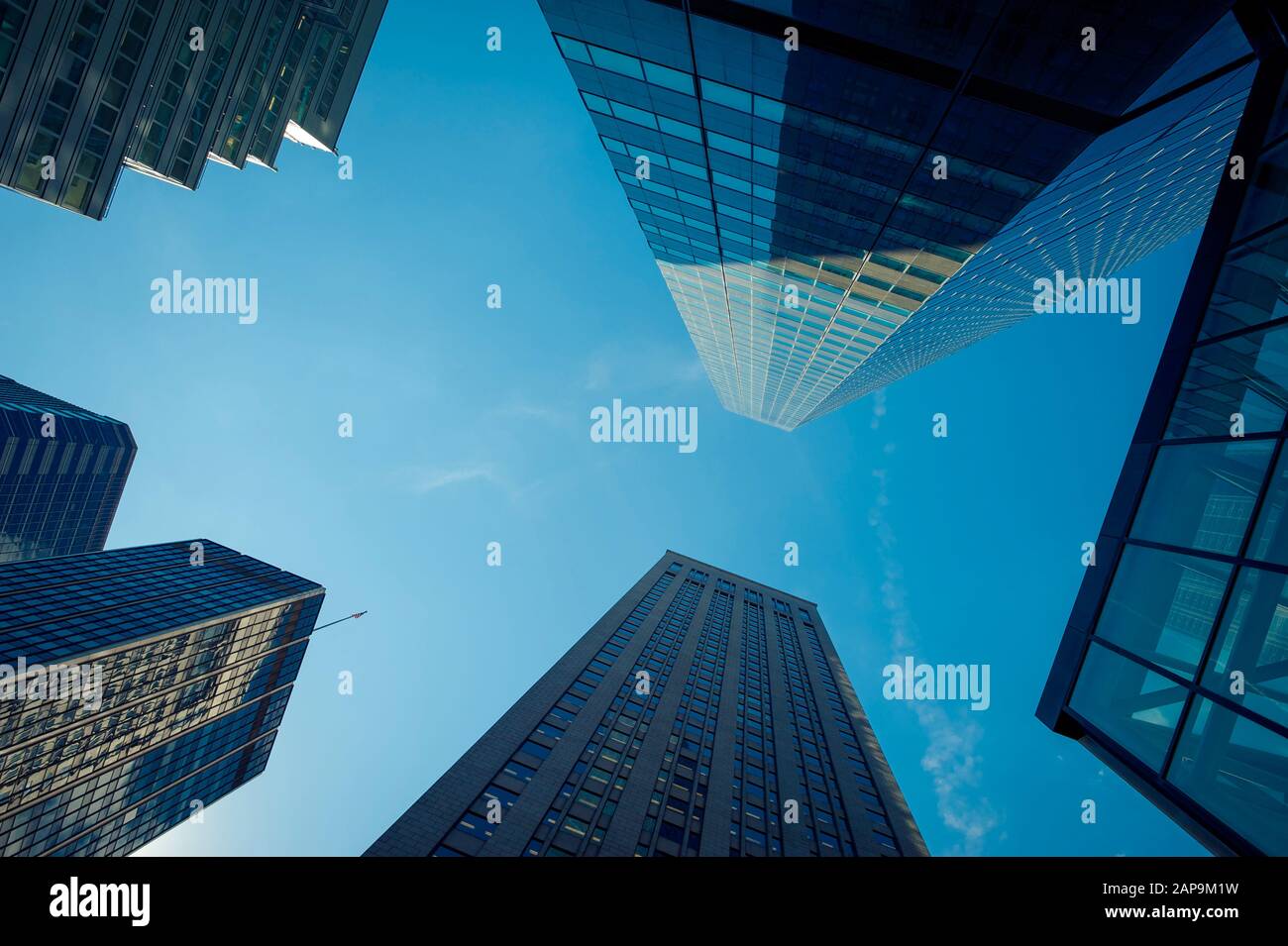 View from below looking up at skyscrapers forming a cross in blue sky ...