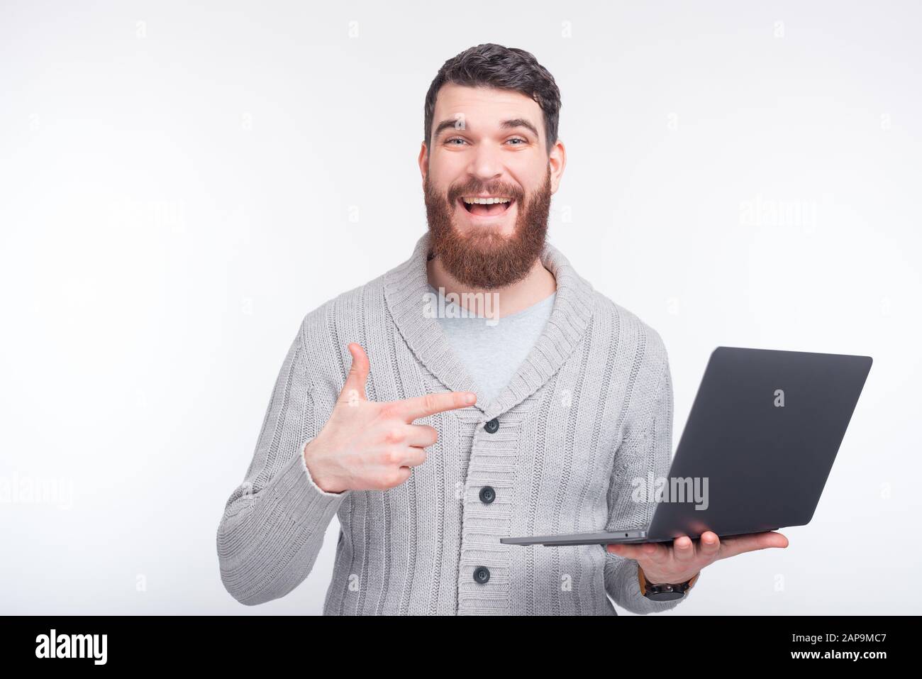 Laughing man is pointing at his laptop showing something on white ...