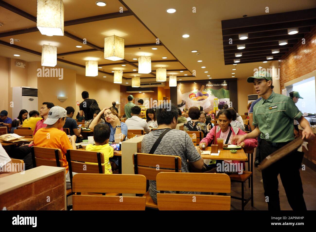 Pasig City, Philippines - January 19, 2020: Customers of a crowded restaurant eat and an ...