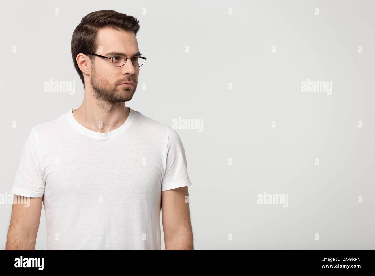 Concentrated young man standing aside looking at empty copy space Stock ...