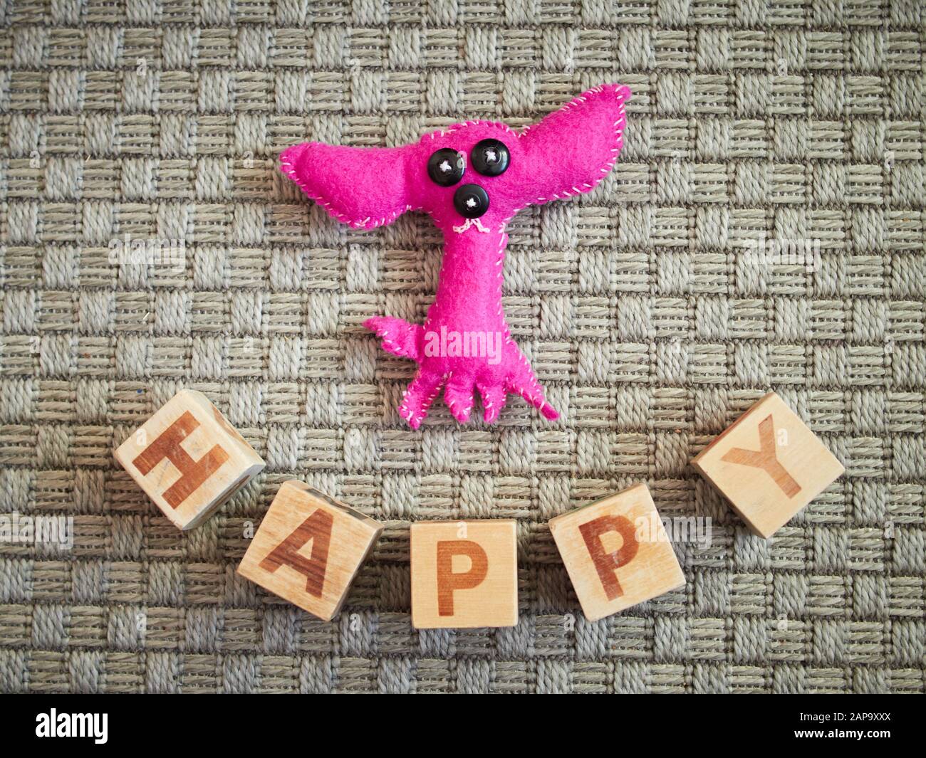 Handmade toy dog and wooden alphabet blocks spelling happy on grey ...