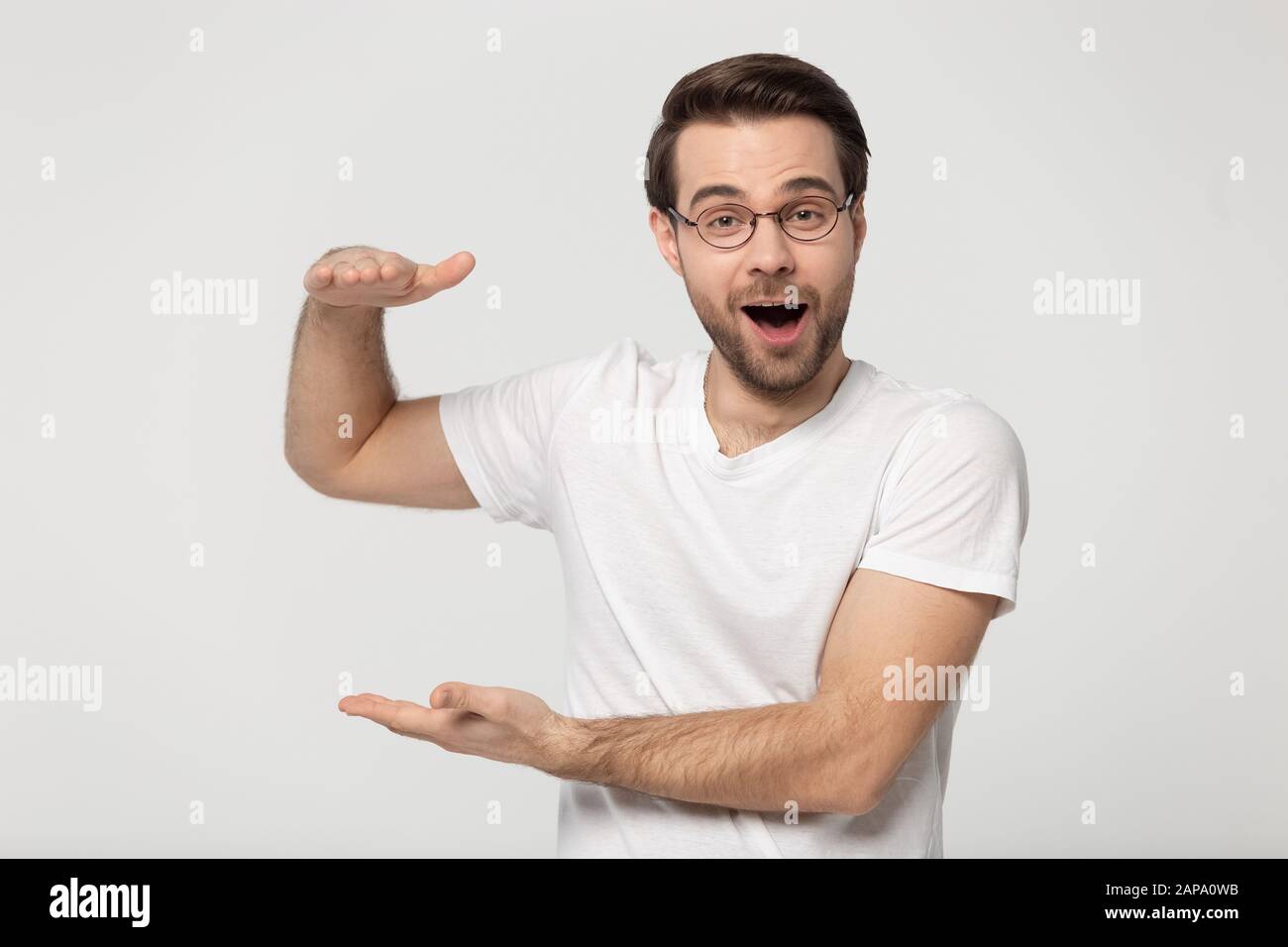 Amazed surprised millennial guy showing big size measurement Stock ...