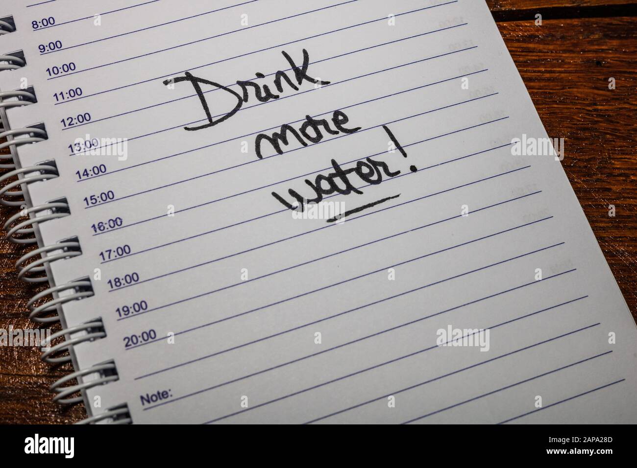 Drink more water, handwriting text on page of office agenda. Copy space ...