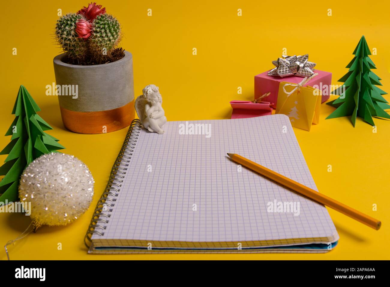 gift box and green origami trees with notepad on yellow desk, table ...