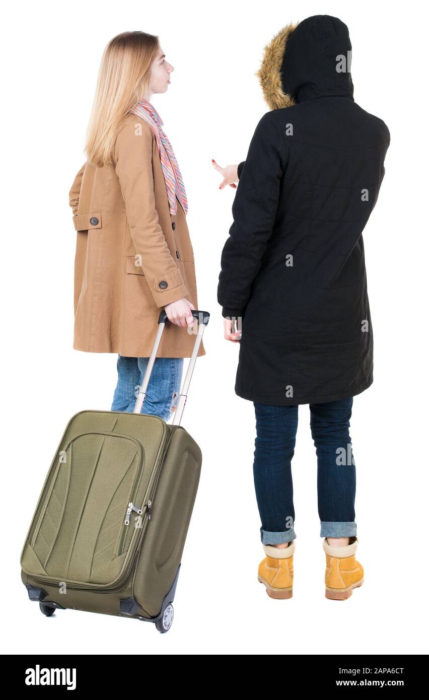 Back view of two woman in winter jacket traveling with suitcas. Back ...