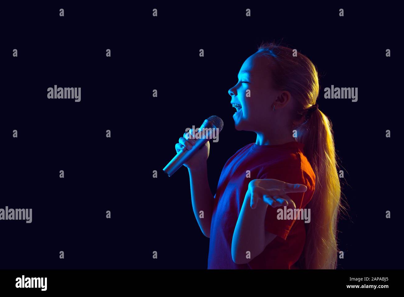 Singing happy. Caucasian girl's portrait on dark studio background in ...