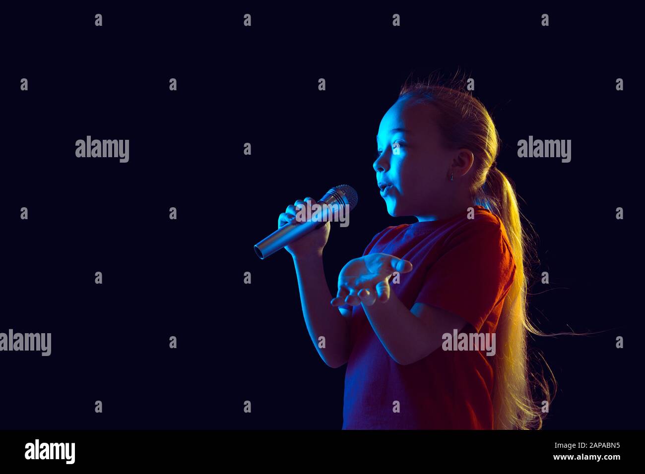 Singing happy. Caucasian girl's portrait on dark studio background in ...