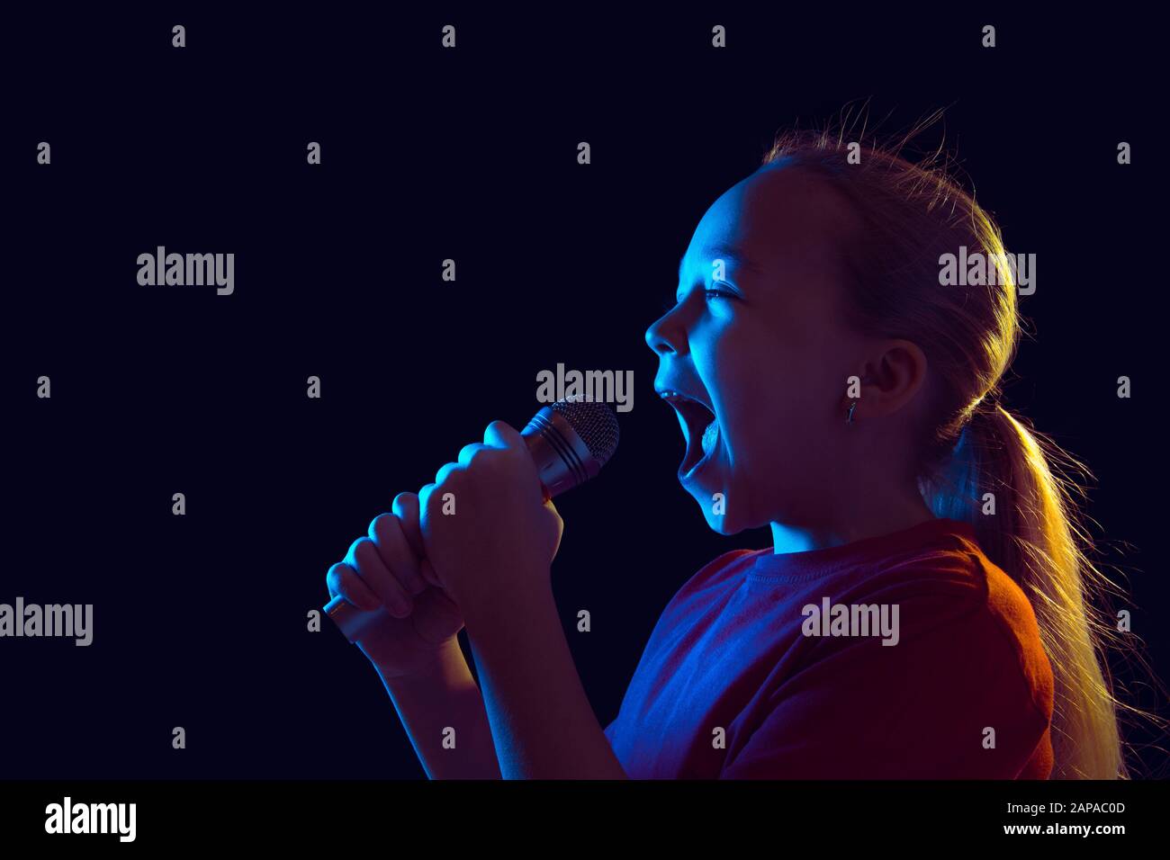 Singing happy. Caucasian girl's portrait on dark studio background in ...