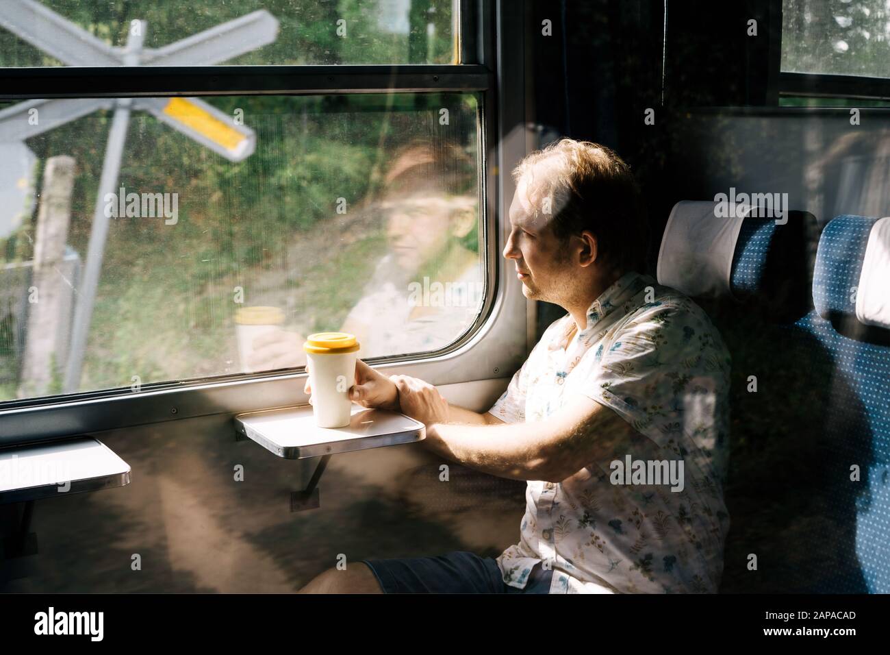 A smiling man in a suburban train looking out the train window Stock ...