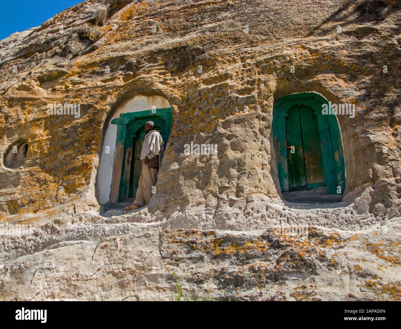 Ethiopian man standing outside entrance to Mikael Milhaizengi rock hewn ...