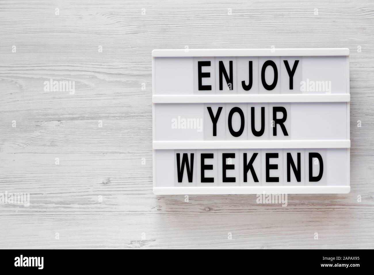 'Enjoy your weekend' words on a lightbox on a white wooden surface, top ...