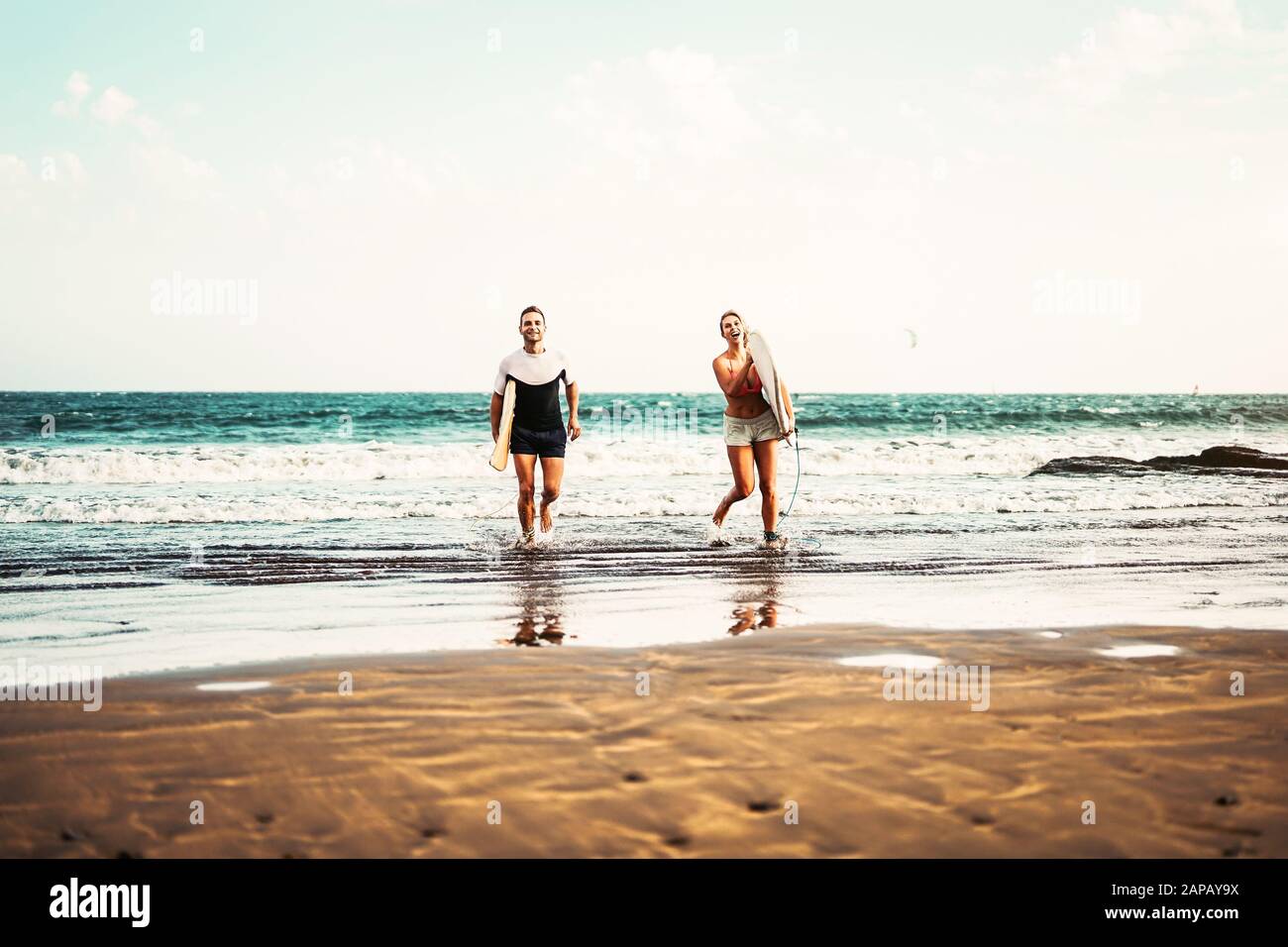 Happy surfers couple running out water after ride on waves - Young ...