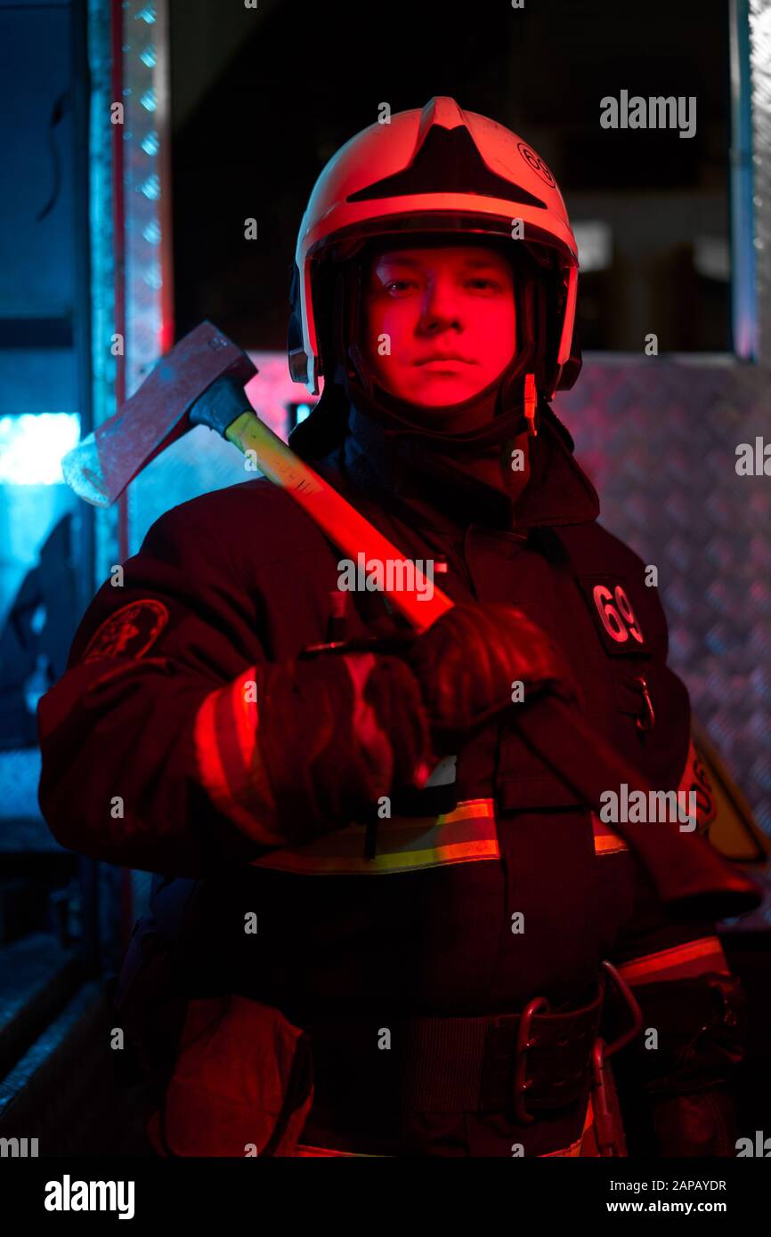 Close up firefighter male with hammer on his shoulder standing near ...