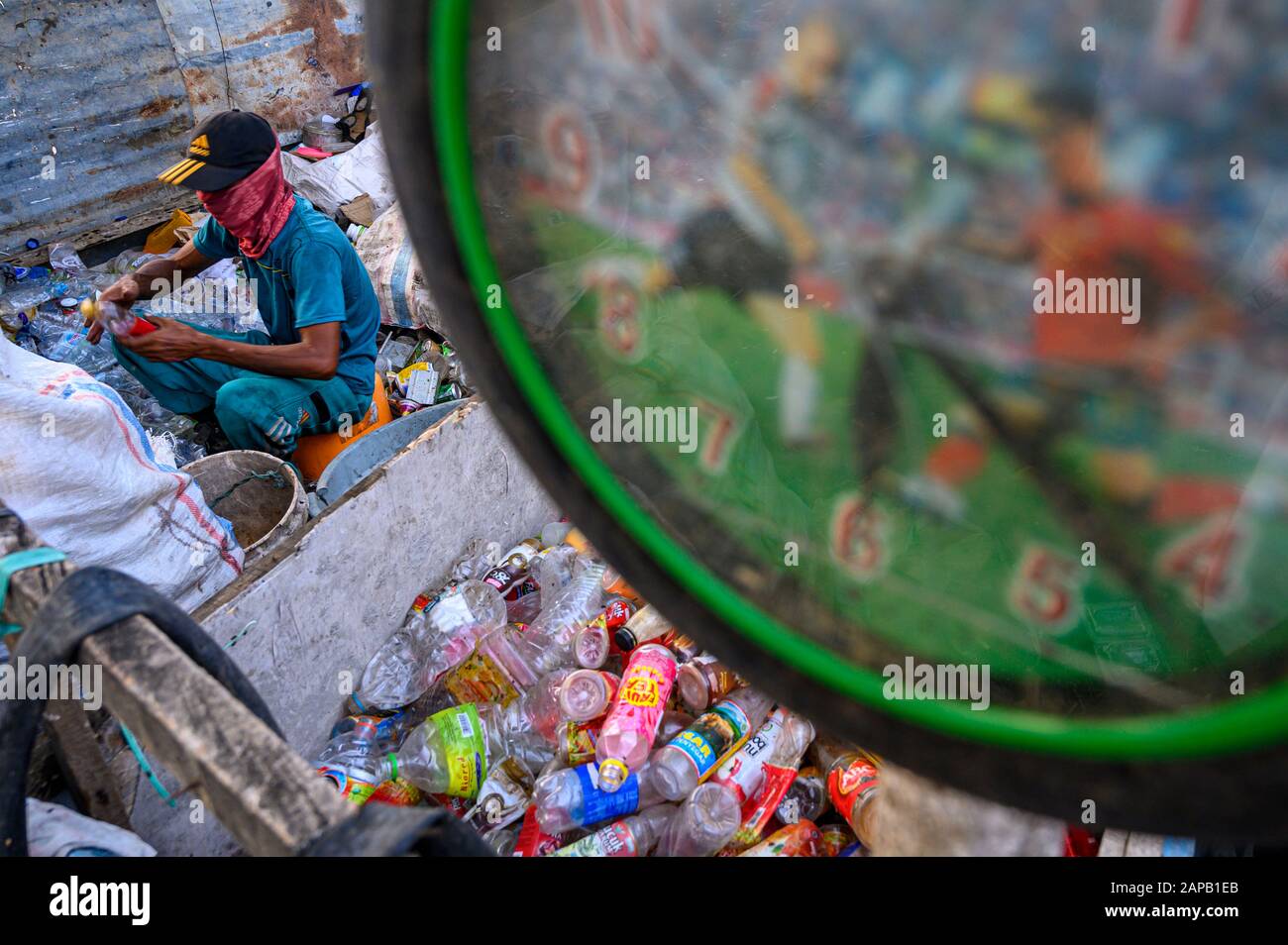 A scavenger sorts out the plastic waste he collects for recycling at ...