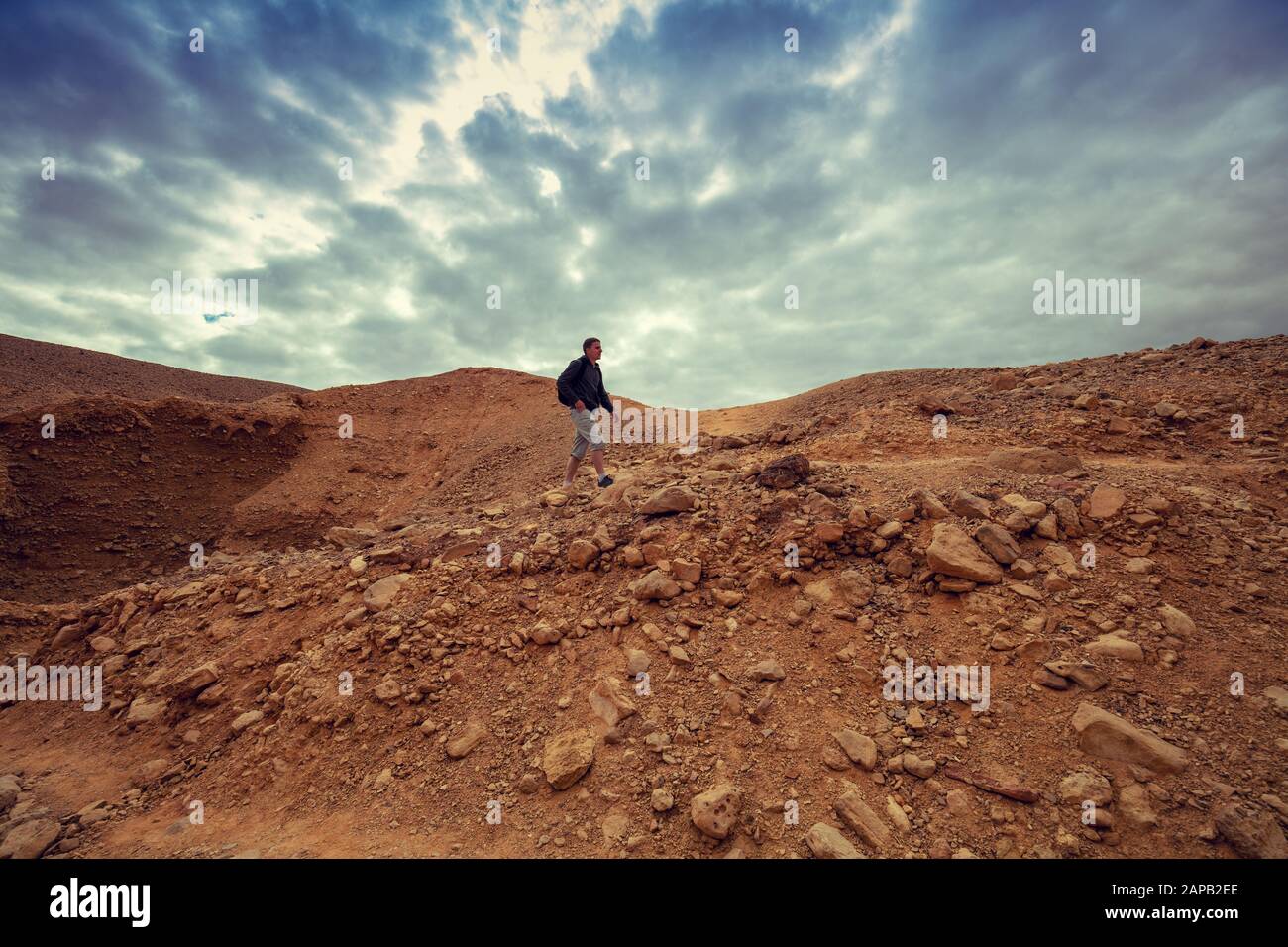 Human hiking in a desert. Desert landscape with dramatic cloudy sky ...