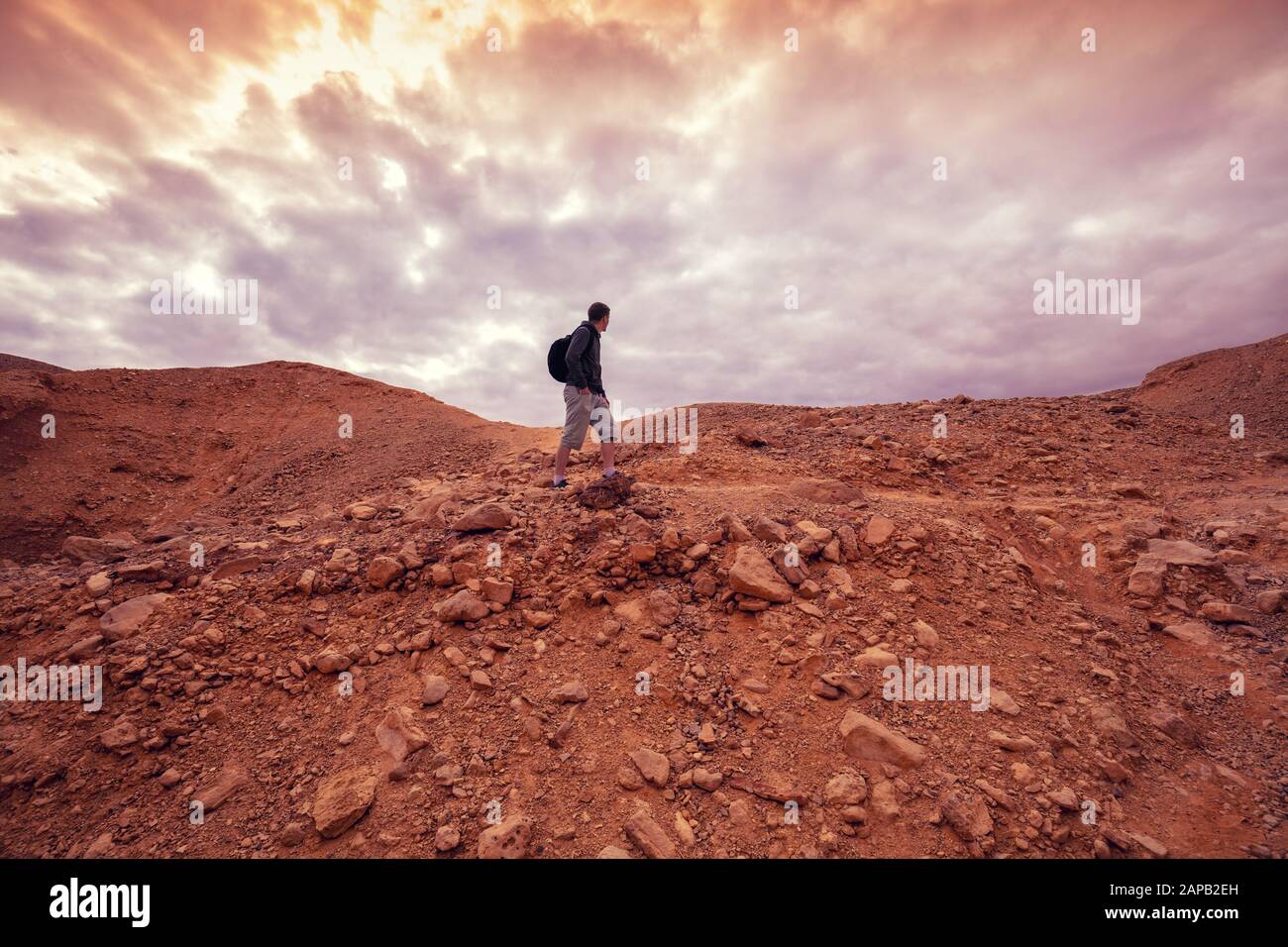 Human hiking in a desert. Desert landscape with dramatic cloudy sky ...