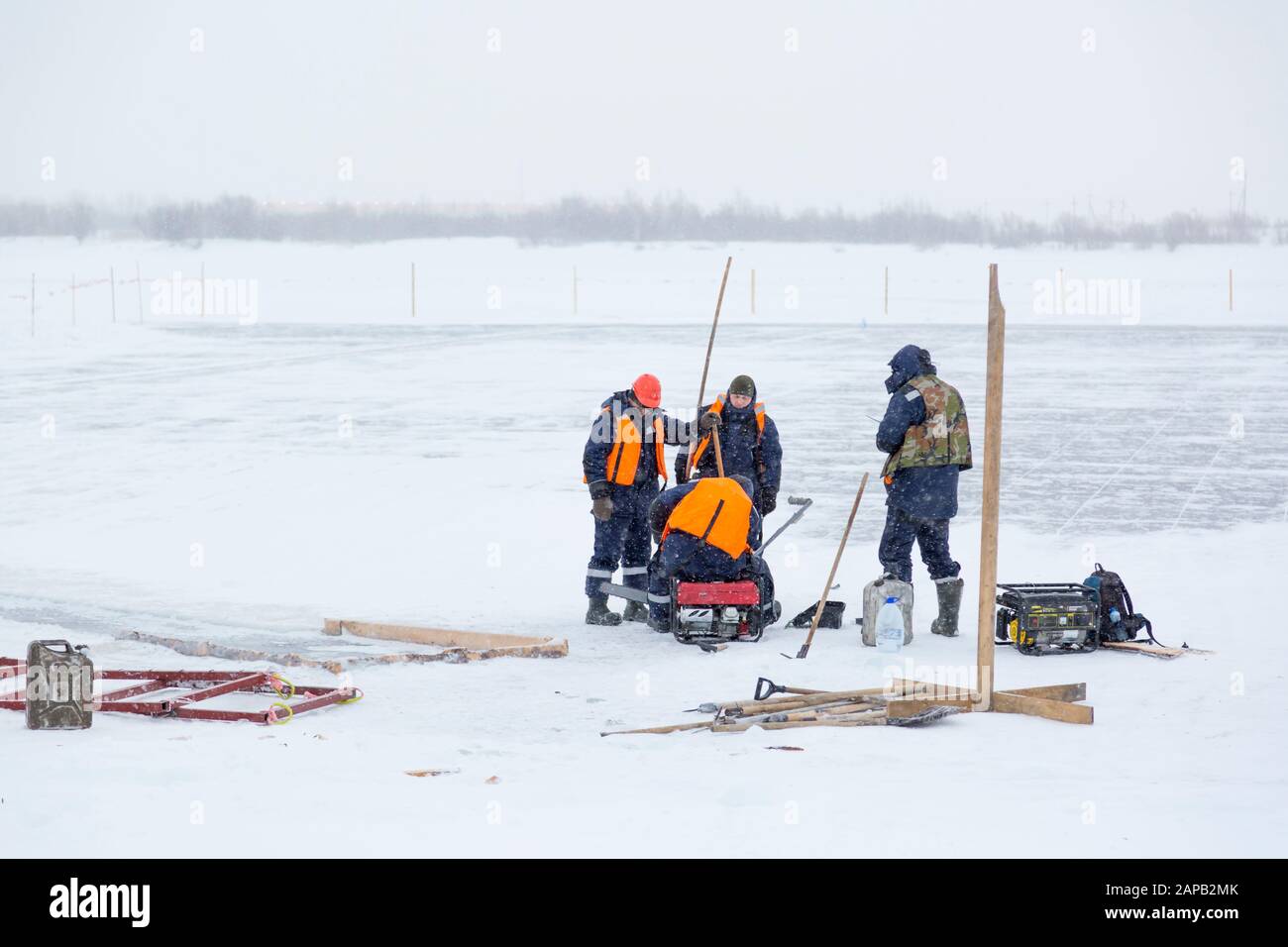 Four workers on the ice of a frozen pond Stock Photo - Alamy