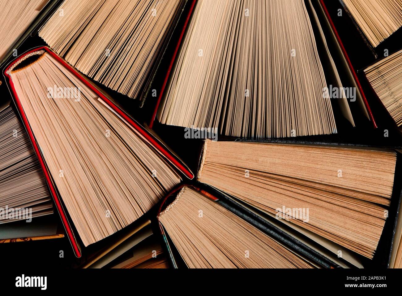 Books. Lots of colourful thick open books stand on a dark background ...