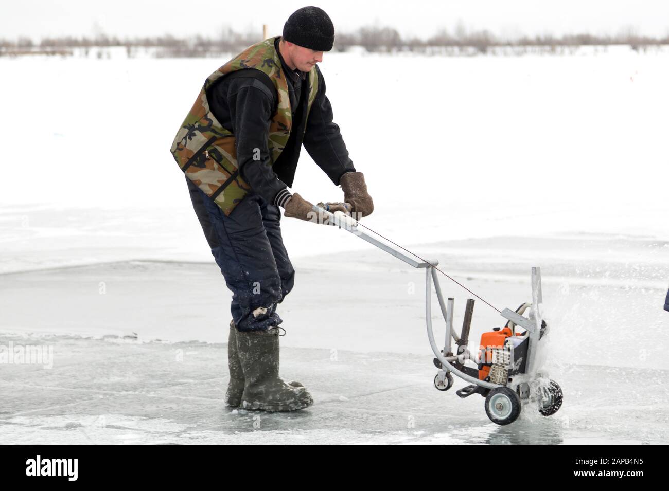 Worker cuts out ice blocks in size on the ice of a frozen lake Stock ...