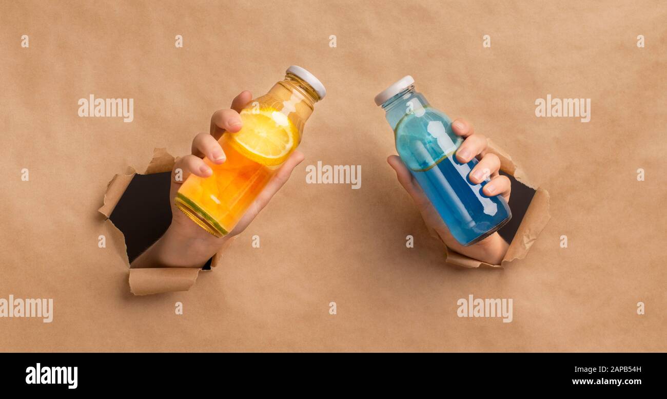 Hands through cardboard holding yellow and blue detox bottles Stock ...