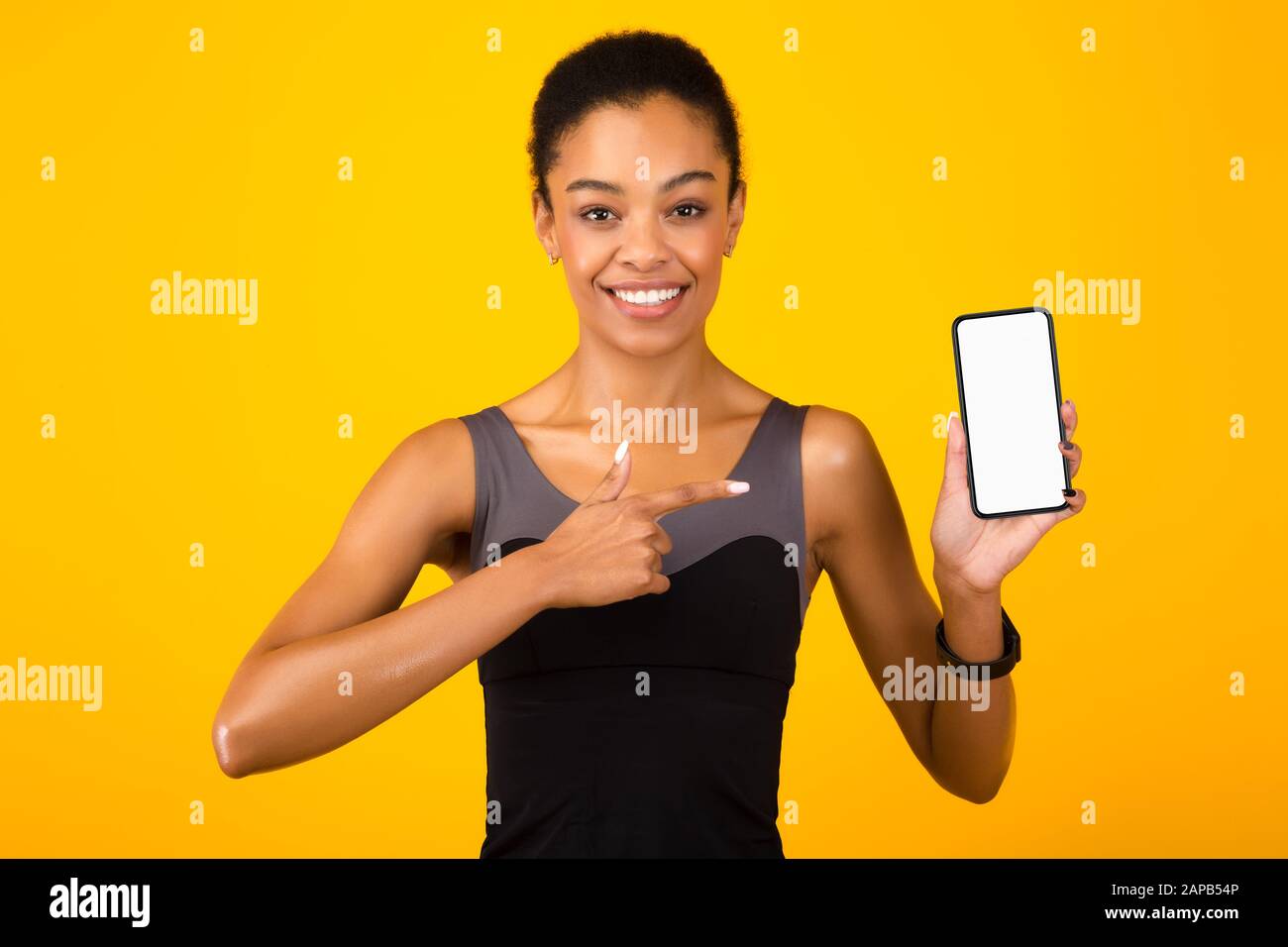 Fit Girl Pointing Finger Showing Smartphone Screen Over Yellow ...