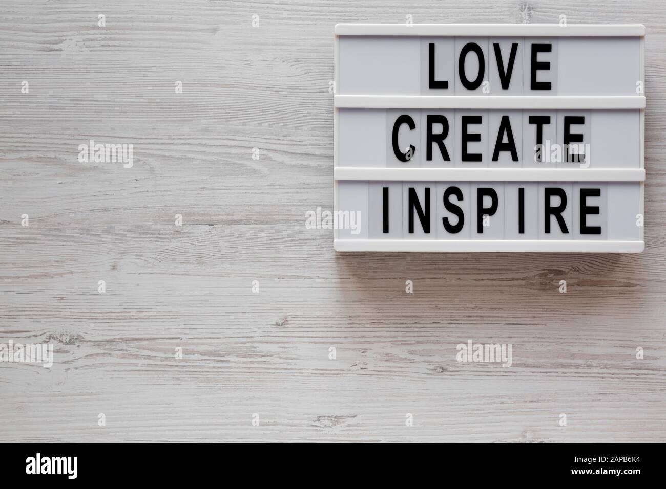 'Love create inspire' words on a modern board on a white wooden ...