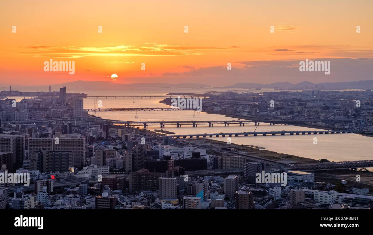Aerial sunset view of Osaka skyline with the river, round sun, and ...
