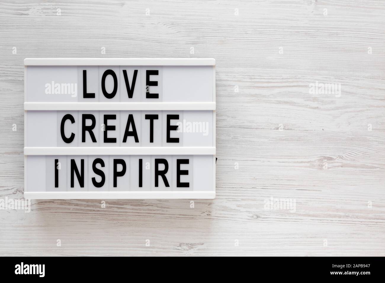 'Love create inspire' words on a lightbox on a white wooden background ...