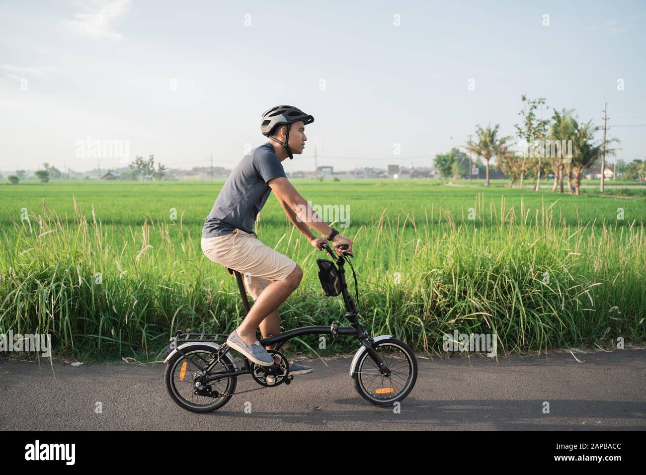 young male wear helmets to ride folding bikes in rice fields background ...