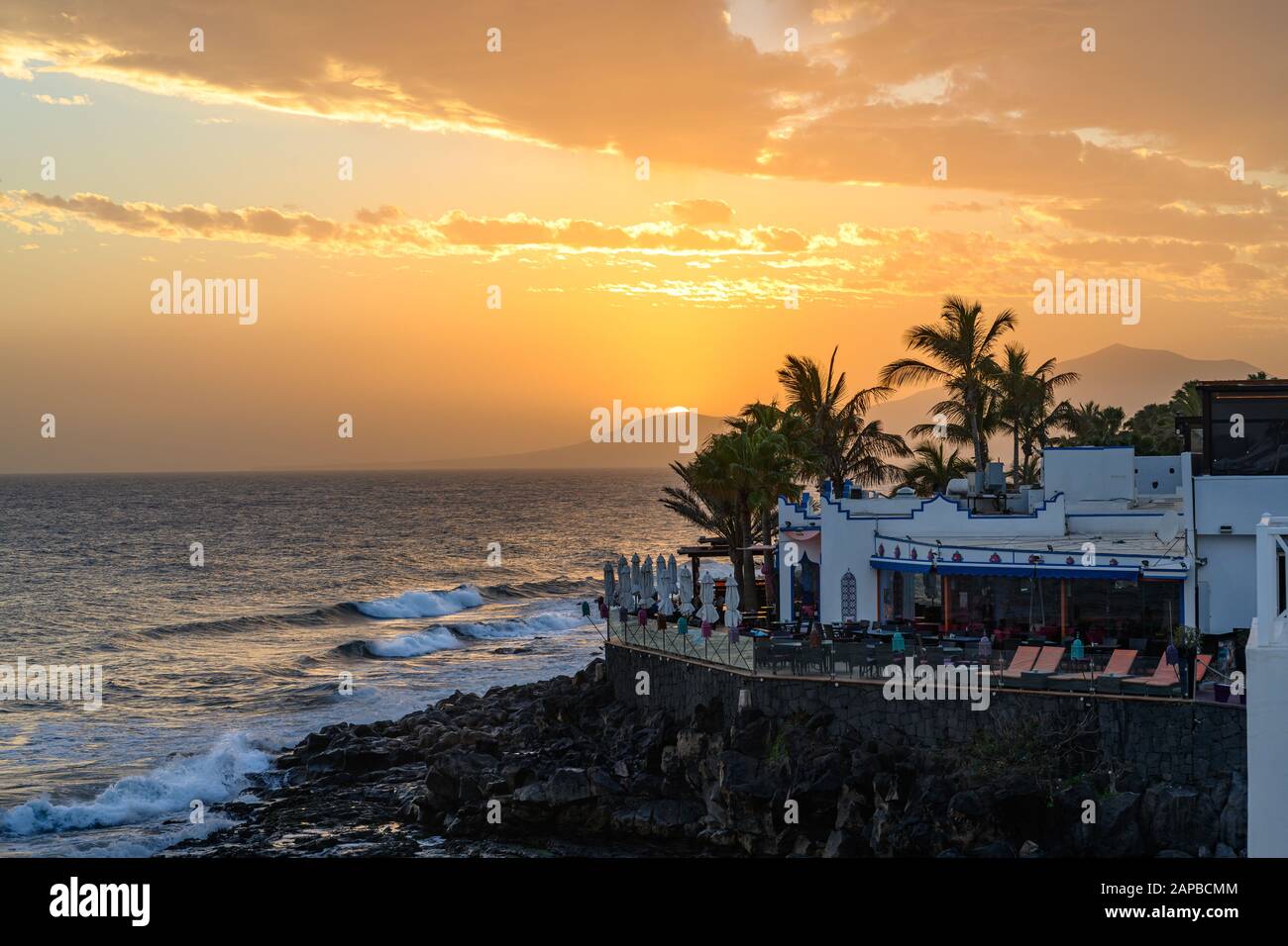 Sun sets over a cafe by the sea shore Stock Photo - Alamy