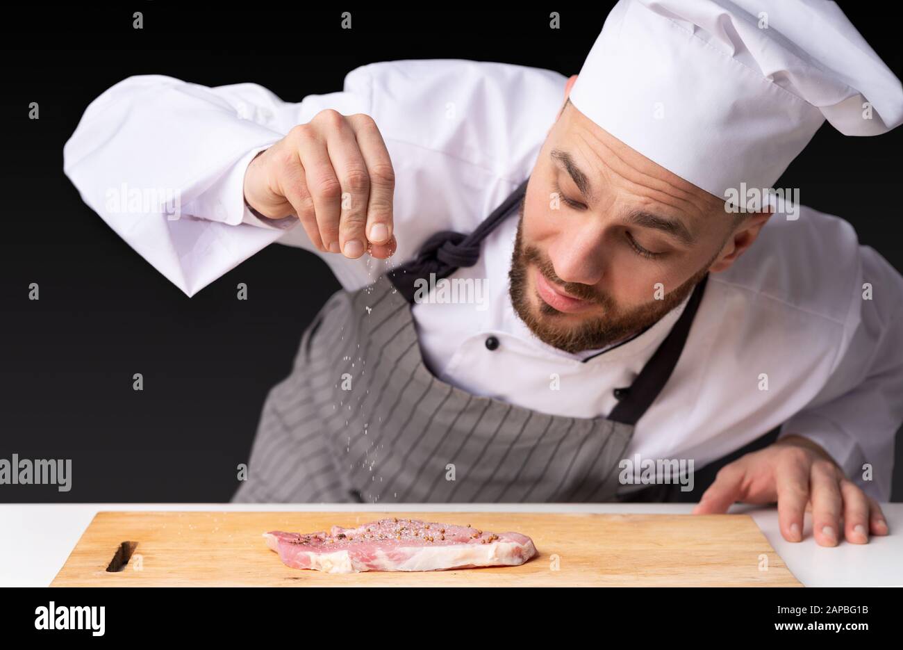 Professional Chef Man Seasoning Steak Standing On Black Studio ...