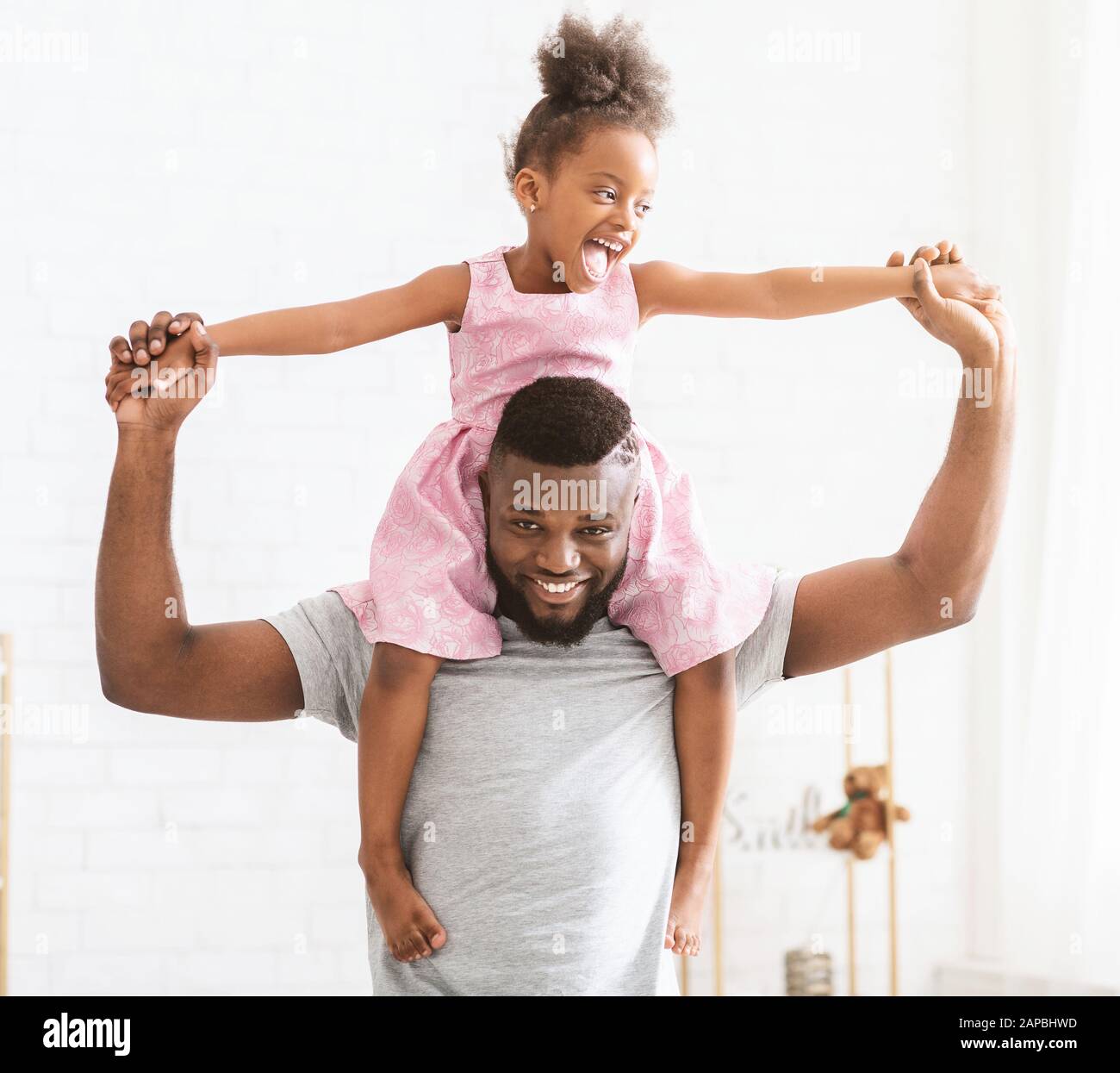 African dad carrying his cute little daughter on shoulders Stock Photo - Alamy