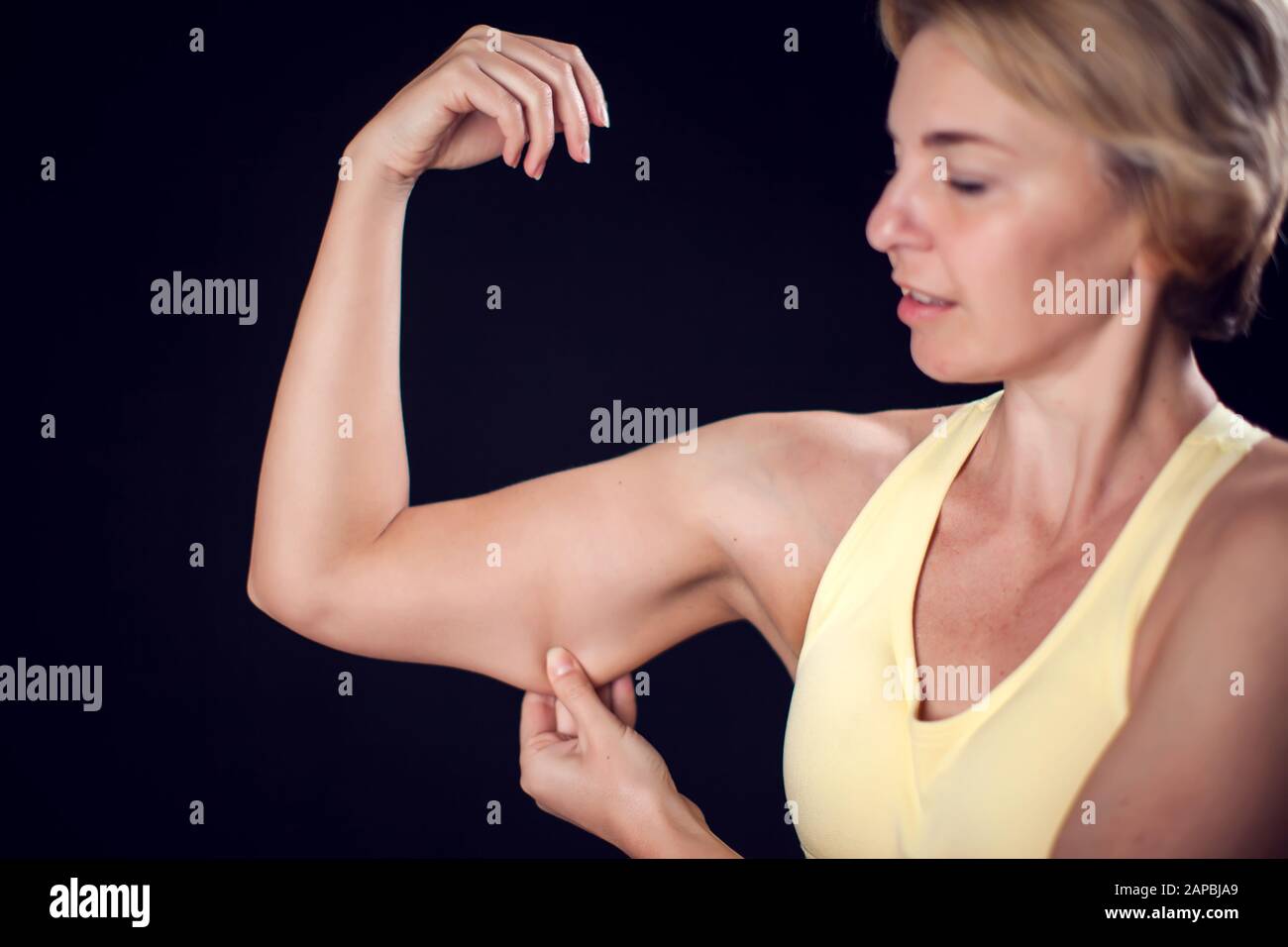 Woman with short blond hair in yellow sport top showing bad shape of ...