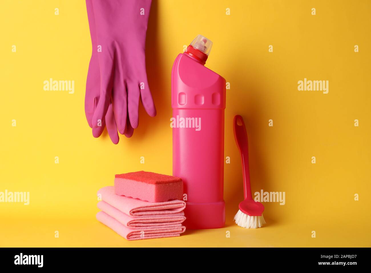 Bottle with detergent and cleaning supplies on yellow background, space ...