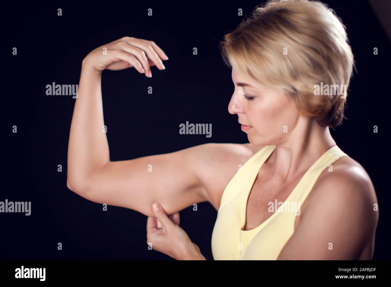 Woman with short blond hair in yellow sport top showing bad shape of ...