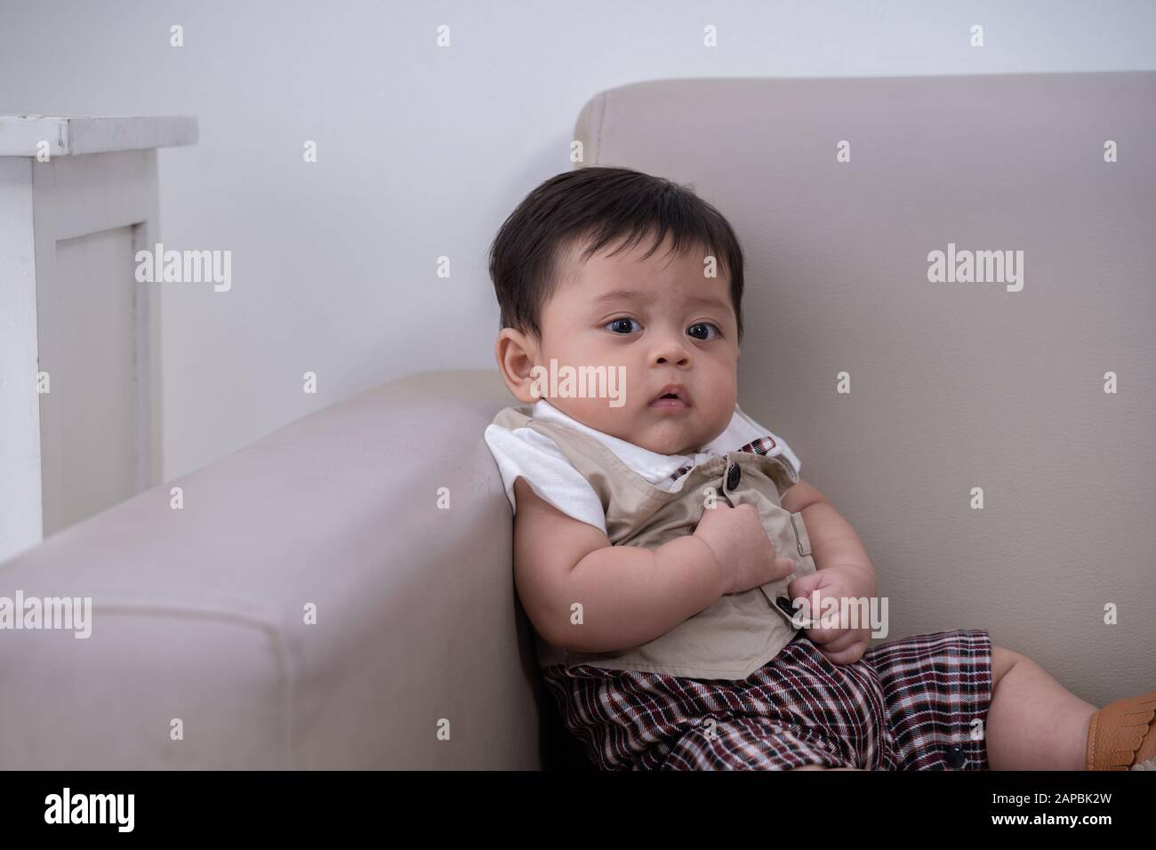 cute little boy sitting alone on couch Stock Photo - Alamy