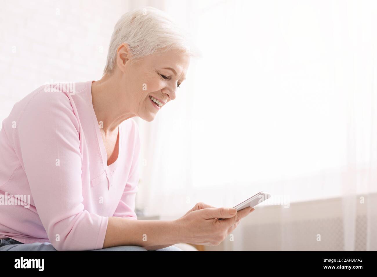 Positive retired lady using modern smartphone at home Stock Photo - Alamy