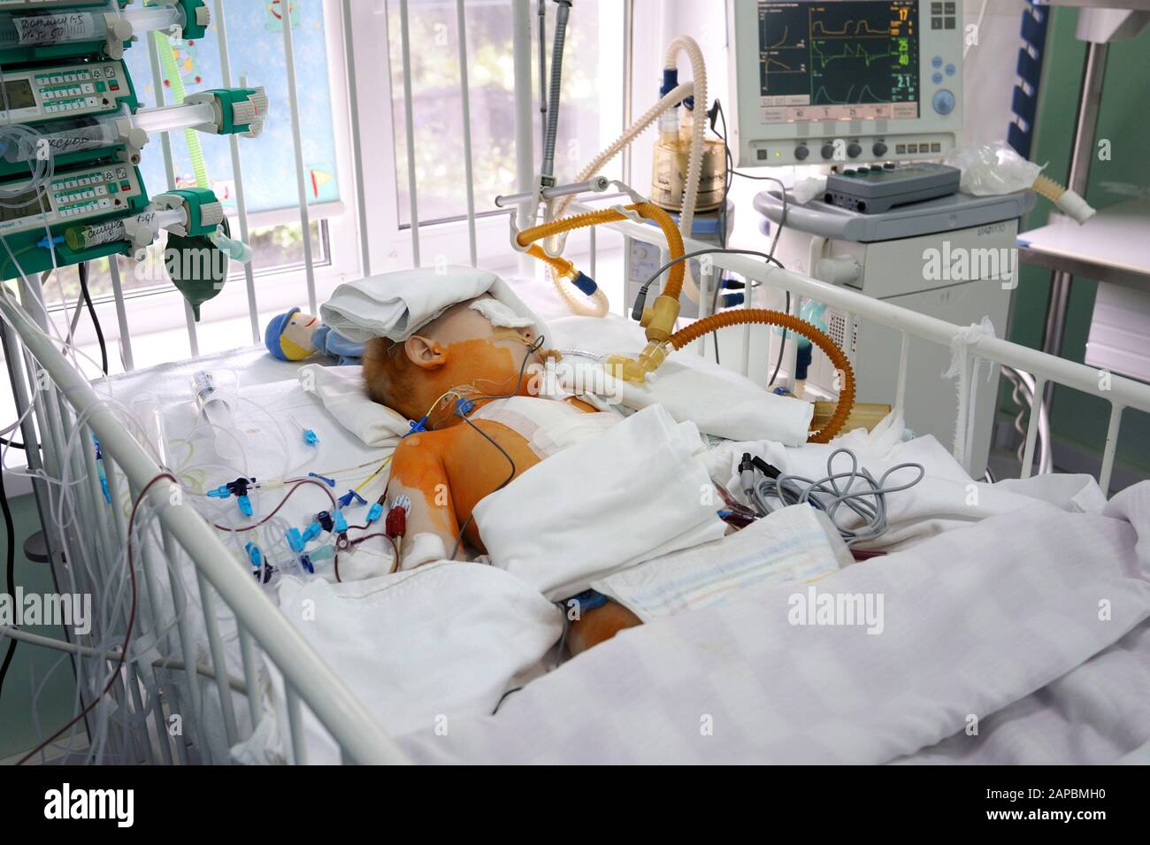 At the intensive care unit. Baby laying on a hospital bed and attached ...