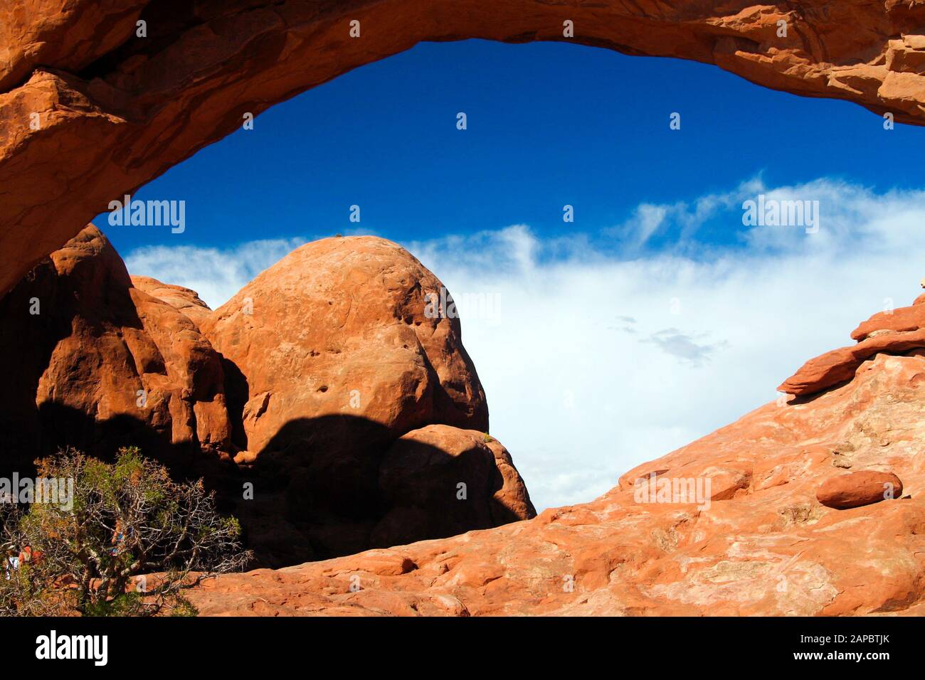 View beyond natural red sandstone arch bridge on rock against blue sky ...