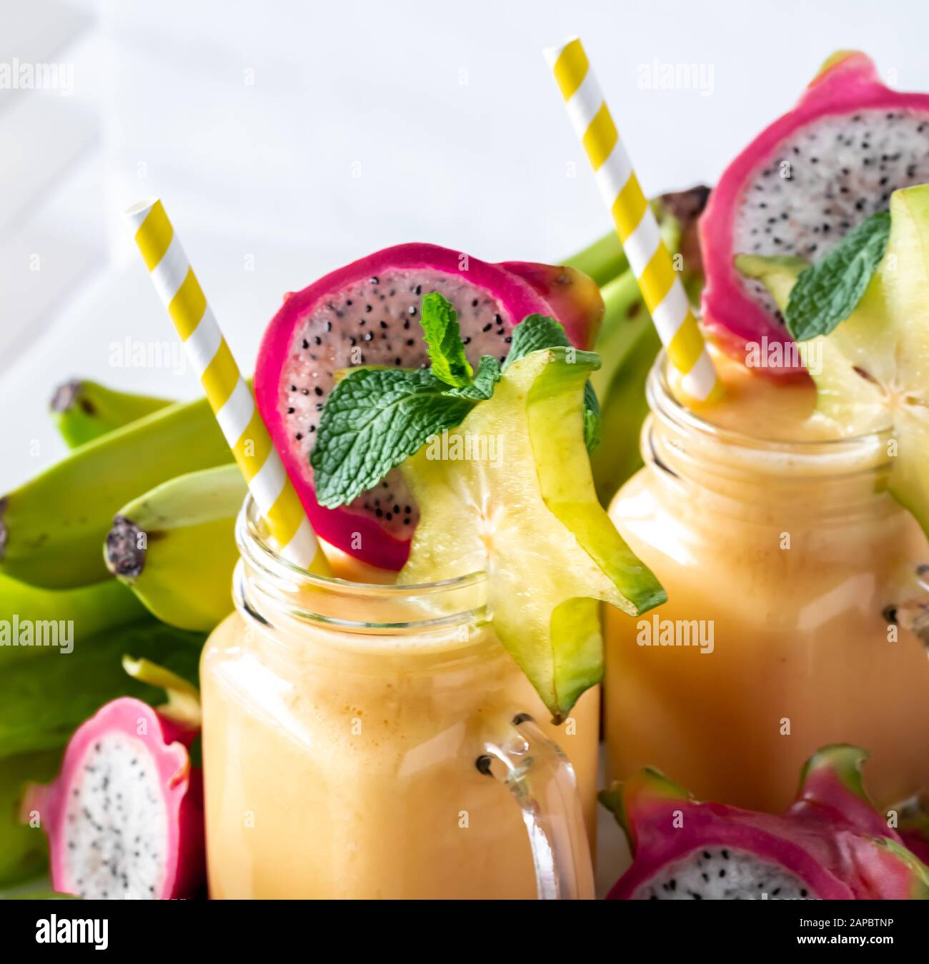 A close up of two glass jars of tropical exotic fruit smoothies ready ...